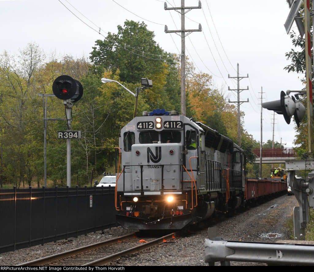 NJT 4112 holds at Station Road's grade crossing while unloading new ties